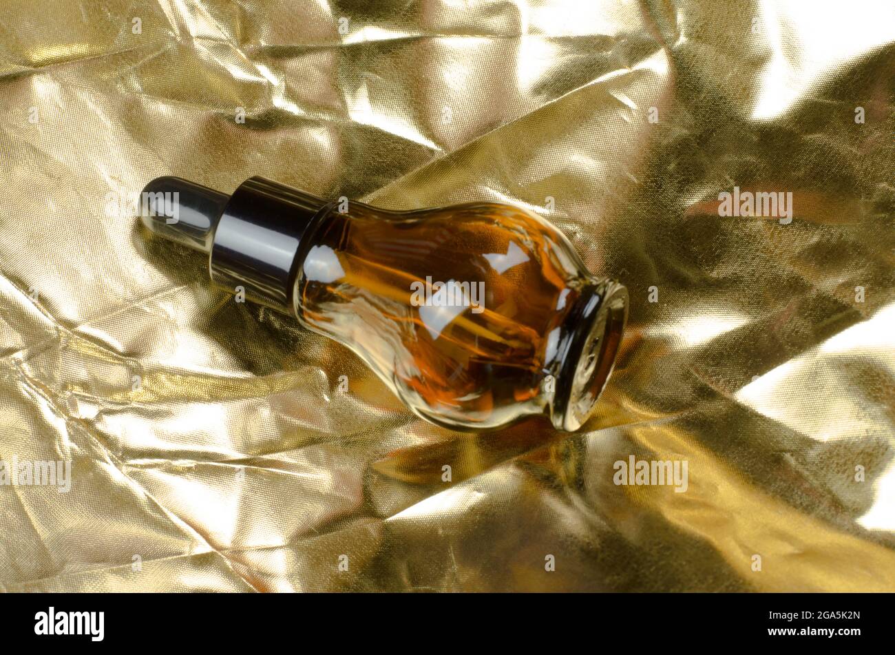 Cosmetic oil in a glass bottle with a dropper on a golden background ...