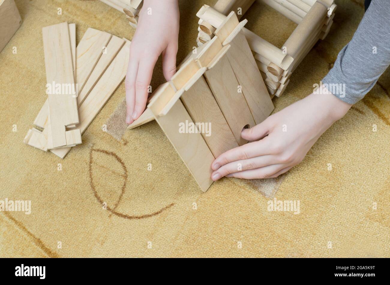 Girl builds a hut from wooden logs, children's wooden constructor Stock ...