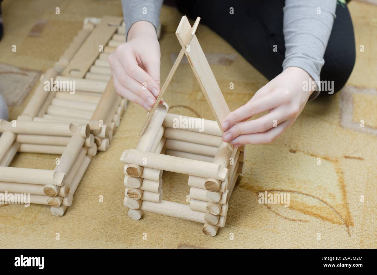 Girl builds a hut from wooden logs, children's wooden constructor Stock ...