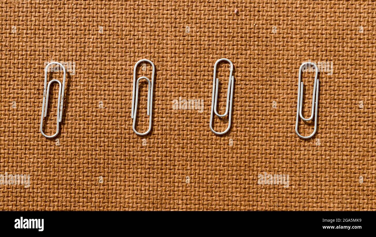 Four James paper clip blinder lying in a row on Brown Color Hard cork ...