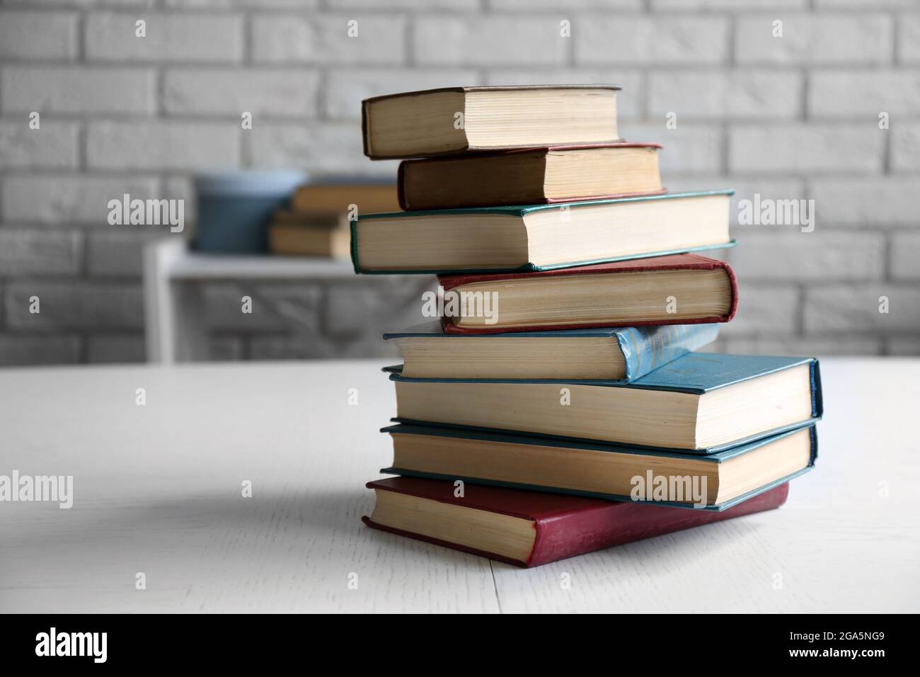 Stack of books on light surface, om bricks wall background Stock Photo ...