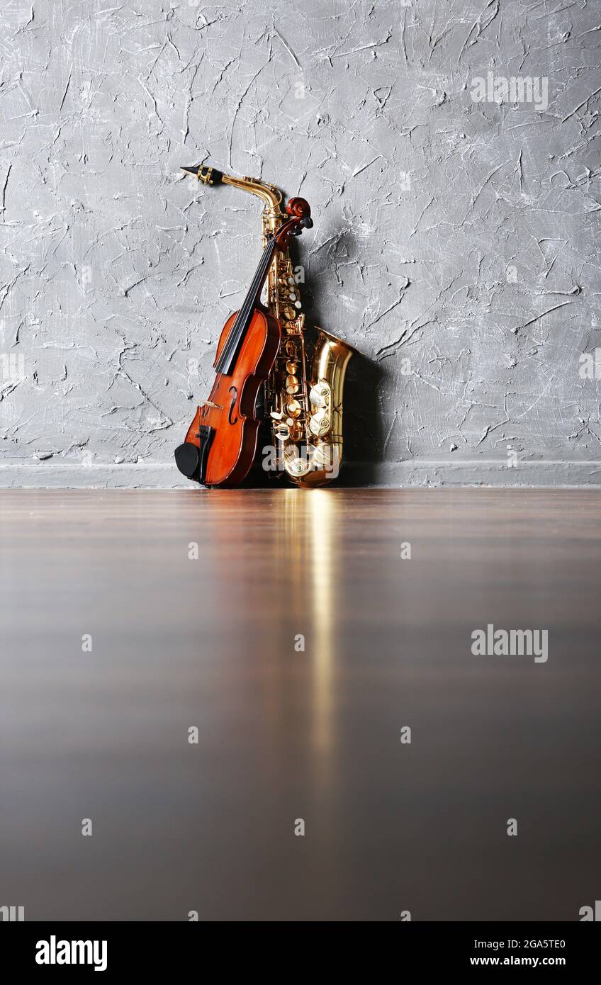 Violin and saxophone on gray wall background Stock Photo - Alamy