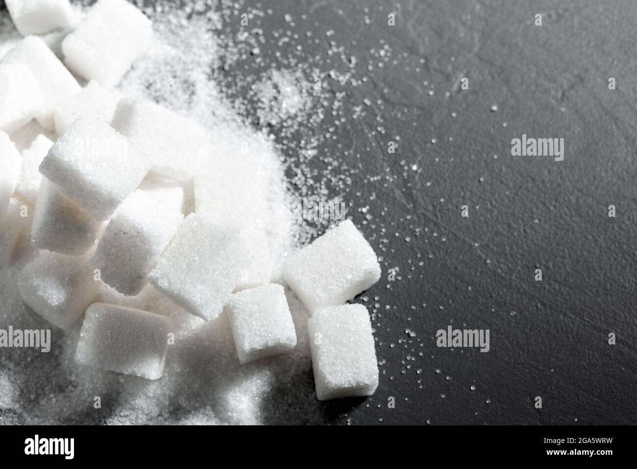 Sugar lumps piled up together against a black background Stock Photo ...