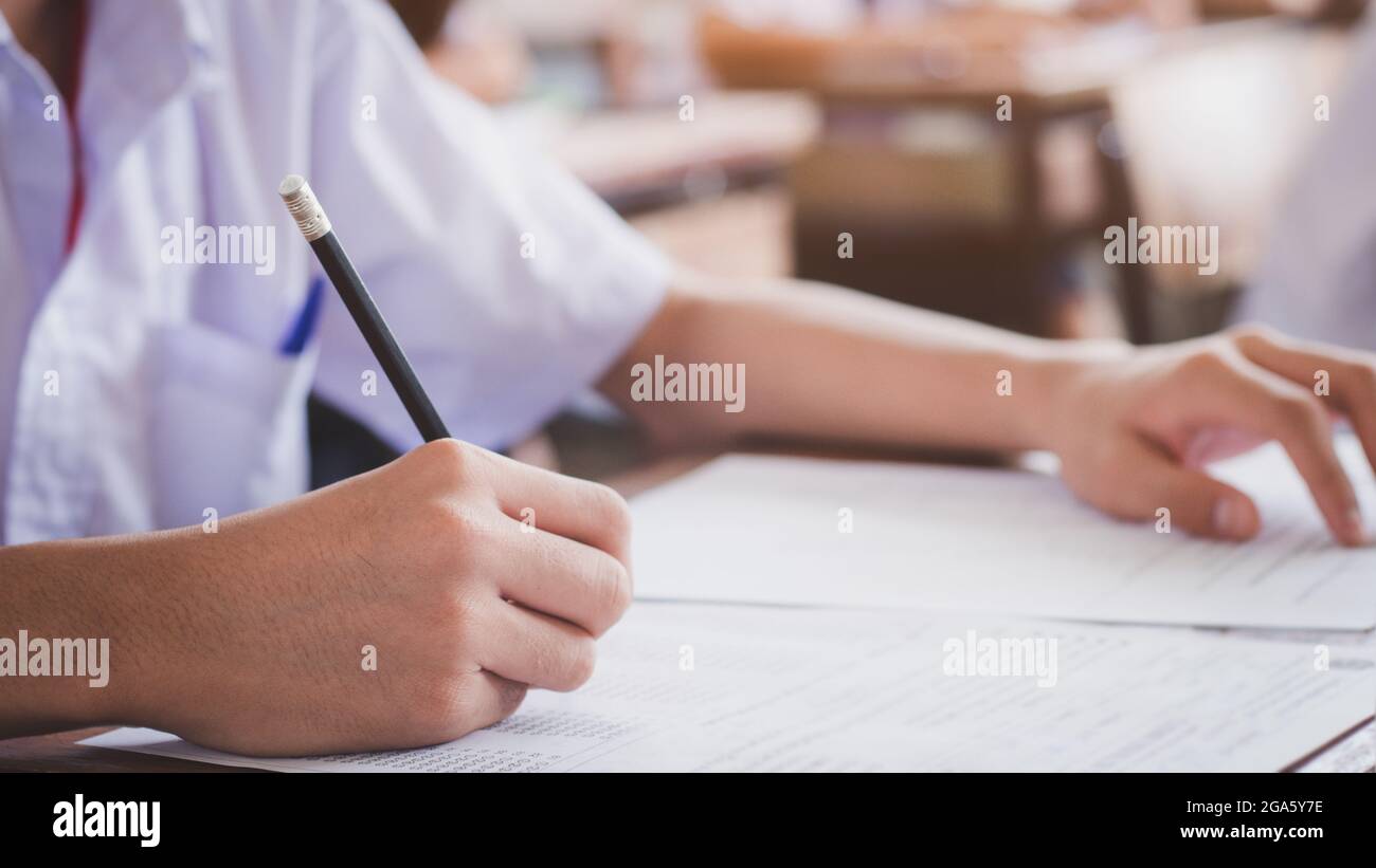 Students writing and reading exam answer sheets exercises in classroom ...