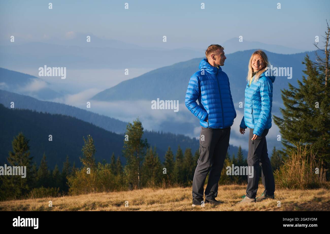 Couple of hikers standing with fun smile on grassy meadow in autumn on ...