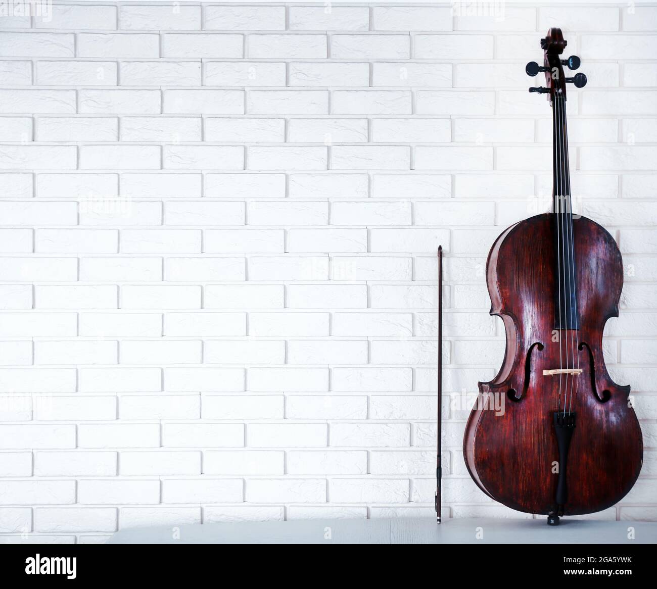 Cello on bricks wall background Stock Photo - Alamy