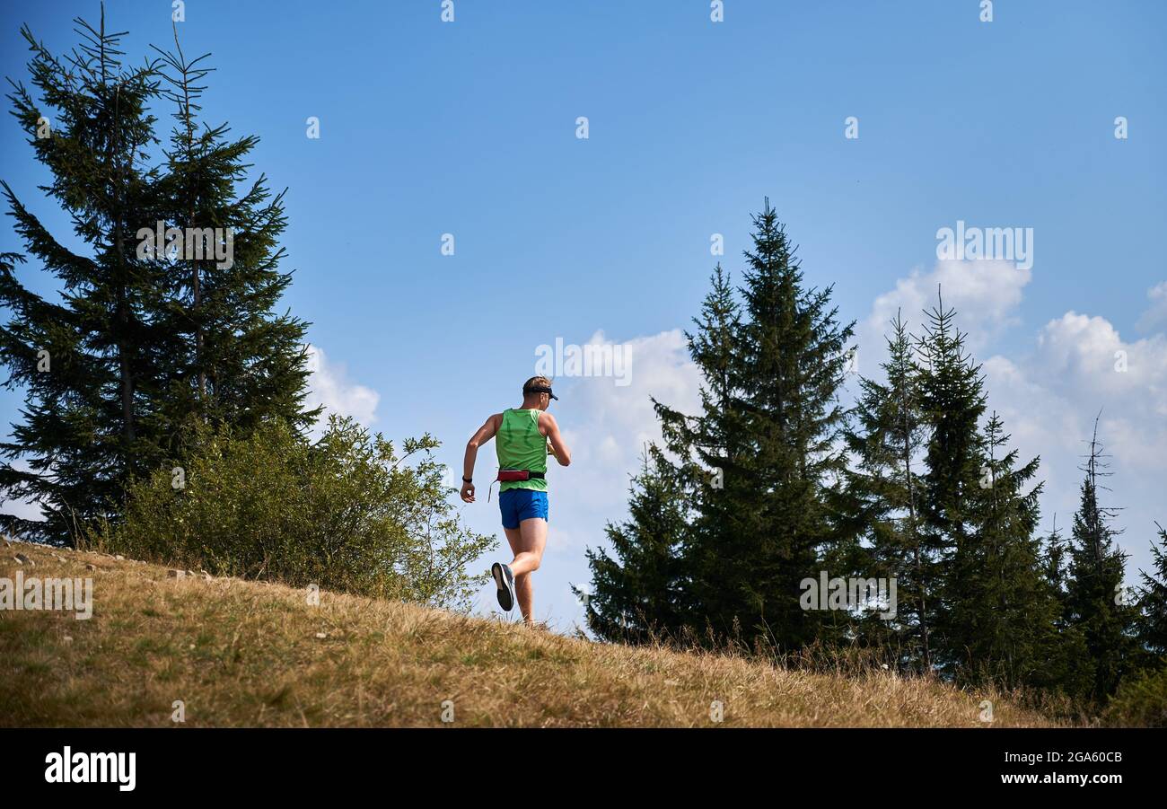 Rear view of male athlete jogging outdoors. Young man in sporty clothes ...