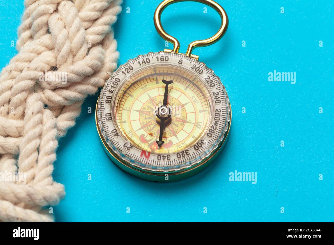 Rope with compass on blue table Stock Photo - Alamy