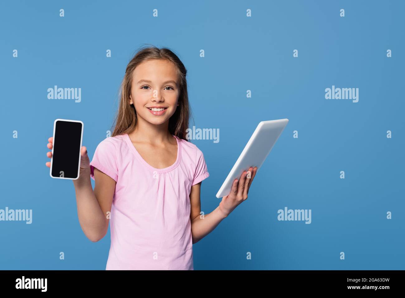 Kid holding digital tablet and showing smartphone isolated on blue ...