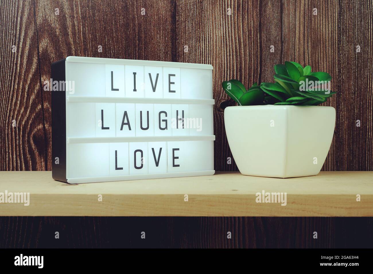 Live Laugh Love word in light box on brick wall and wooden shelves ...