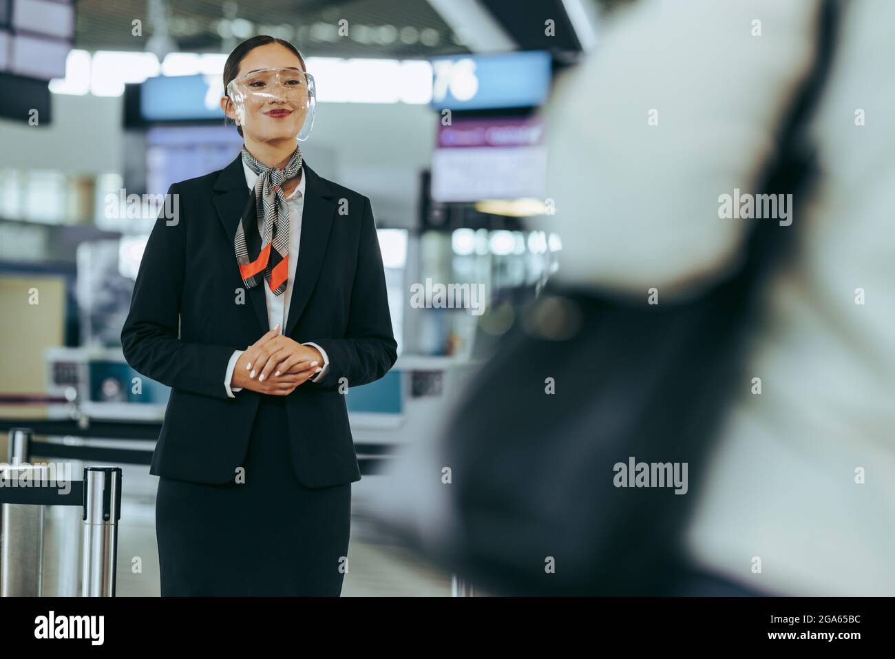 Flight attendant with face shield standing at airport. Airport staff ...