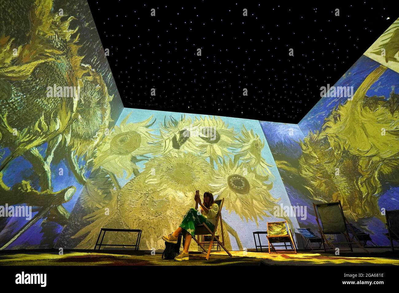 A woman films a projection which is part of the Van Gogh: The Immersive ...