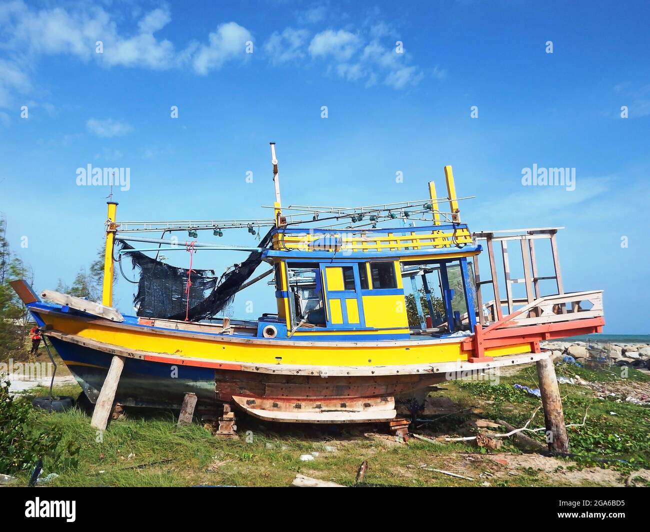 An old bright yellow wooden fishing boat on land Stock Photo - Alamy