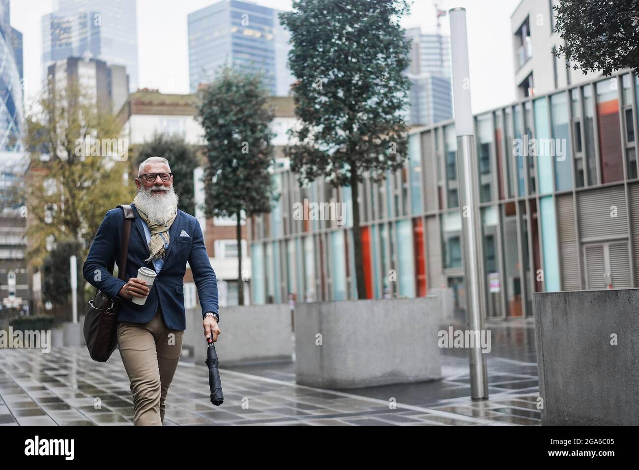 Business hipster senior man walking to work with city in background ...