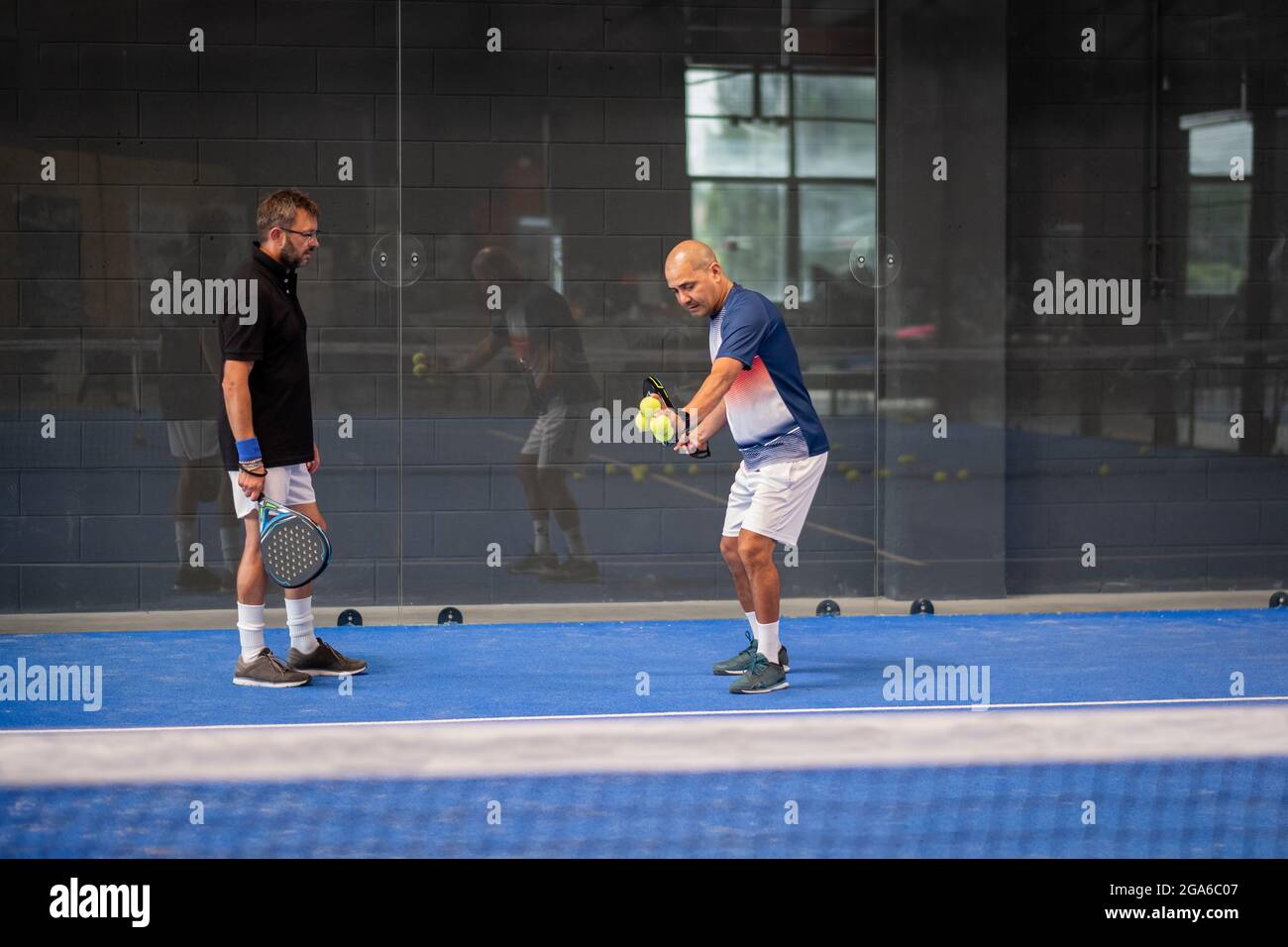 Monitor teaching padel class to man, his student - Trainer teaches boy ...