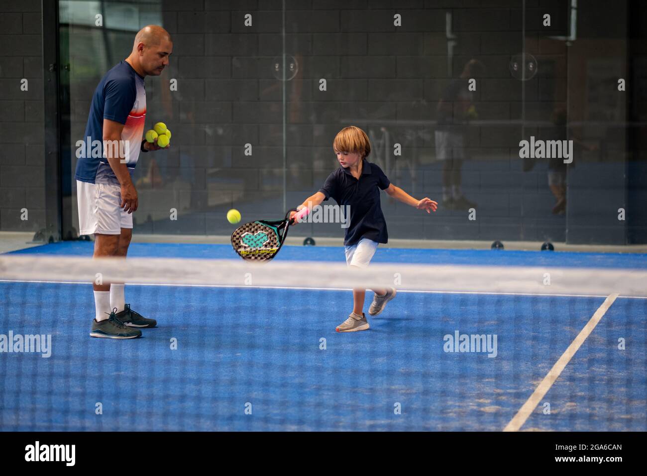 Monitor teaching padel class to child, his student - Trainer teaches ...