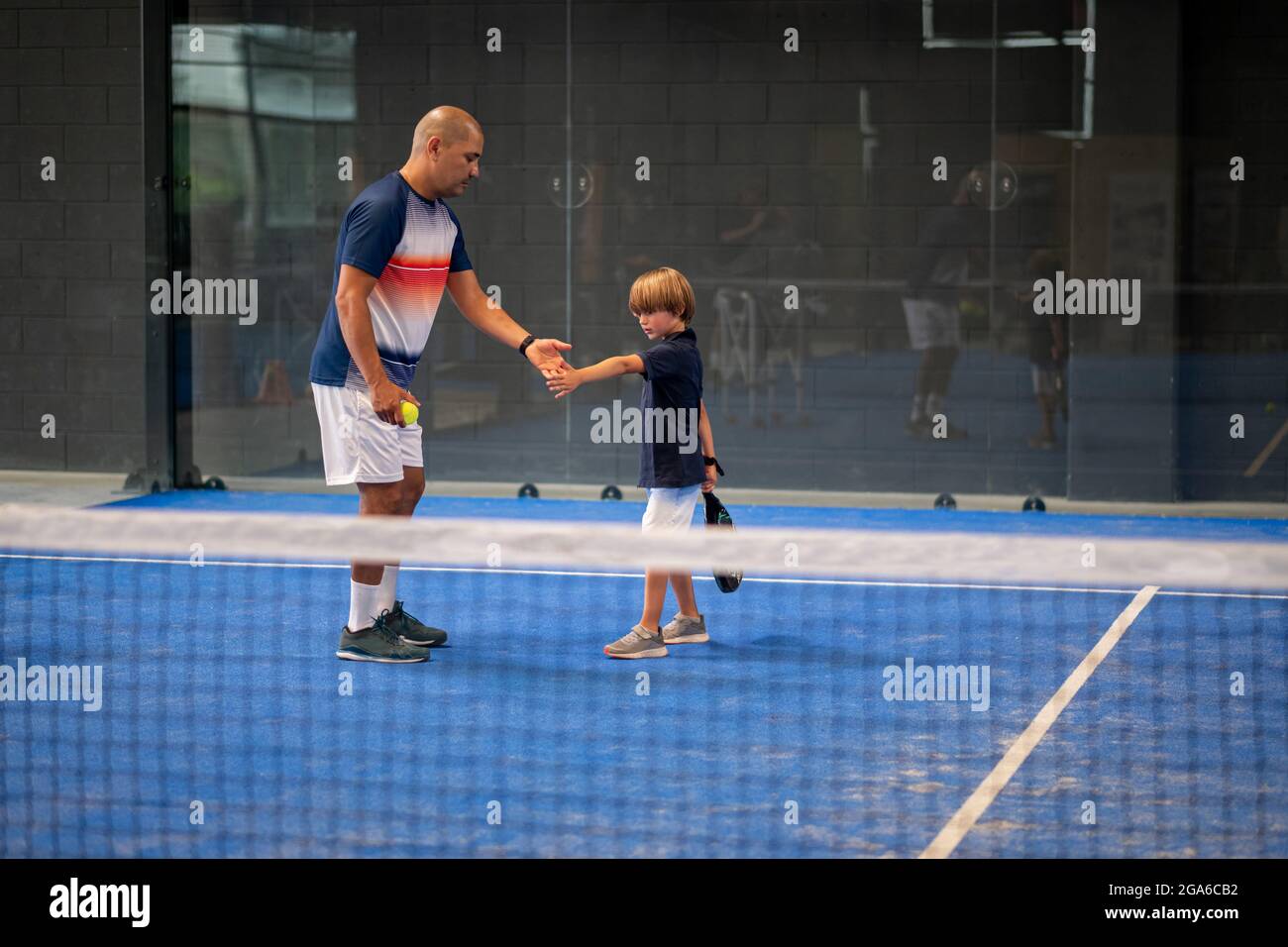 Monitor teaching padel class to child, his student - Trainer teaches ...