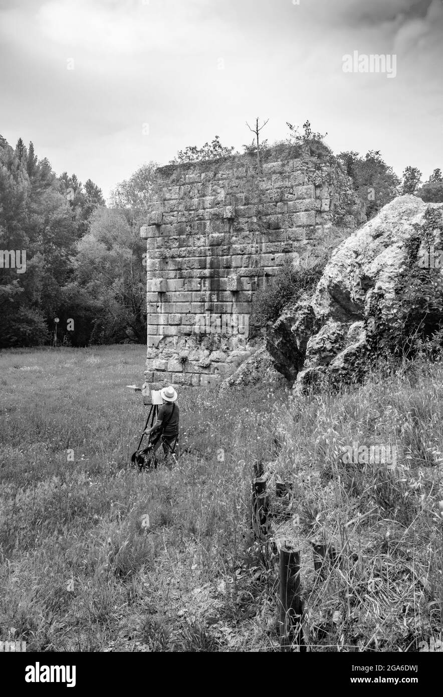 An artist paints live the ruins of the Roman arch bridge of Augustus ...