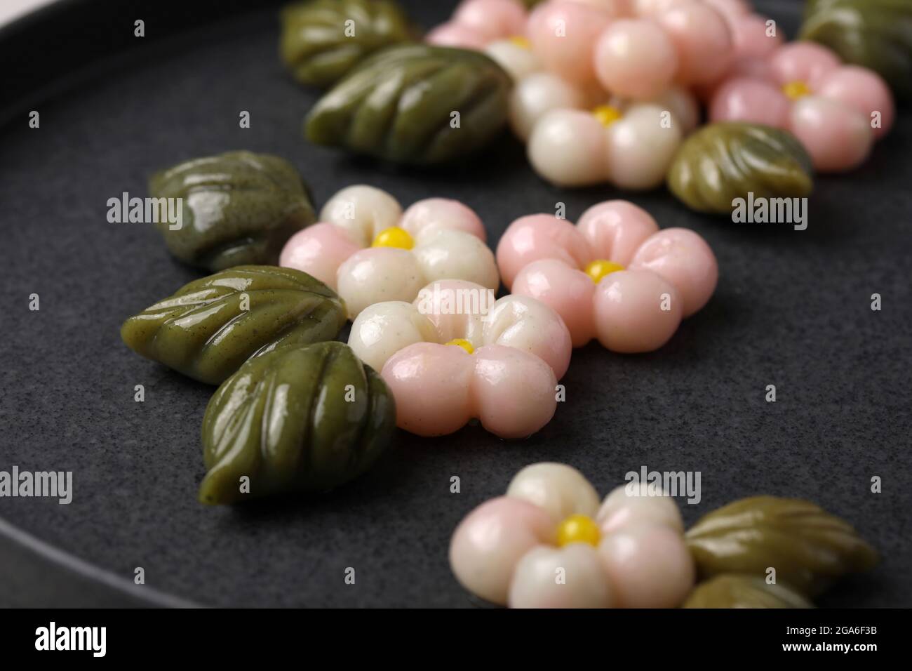 Close-of flower rice cake on black plate Stock Photo - Alamy
