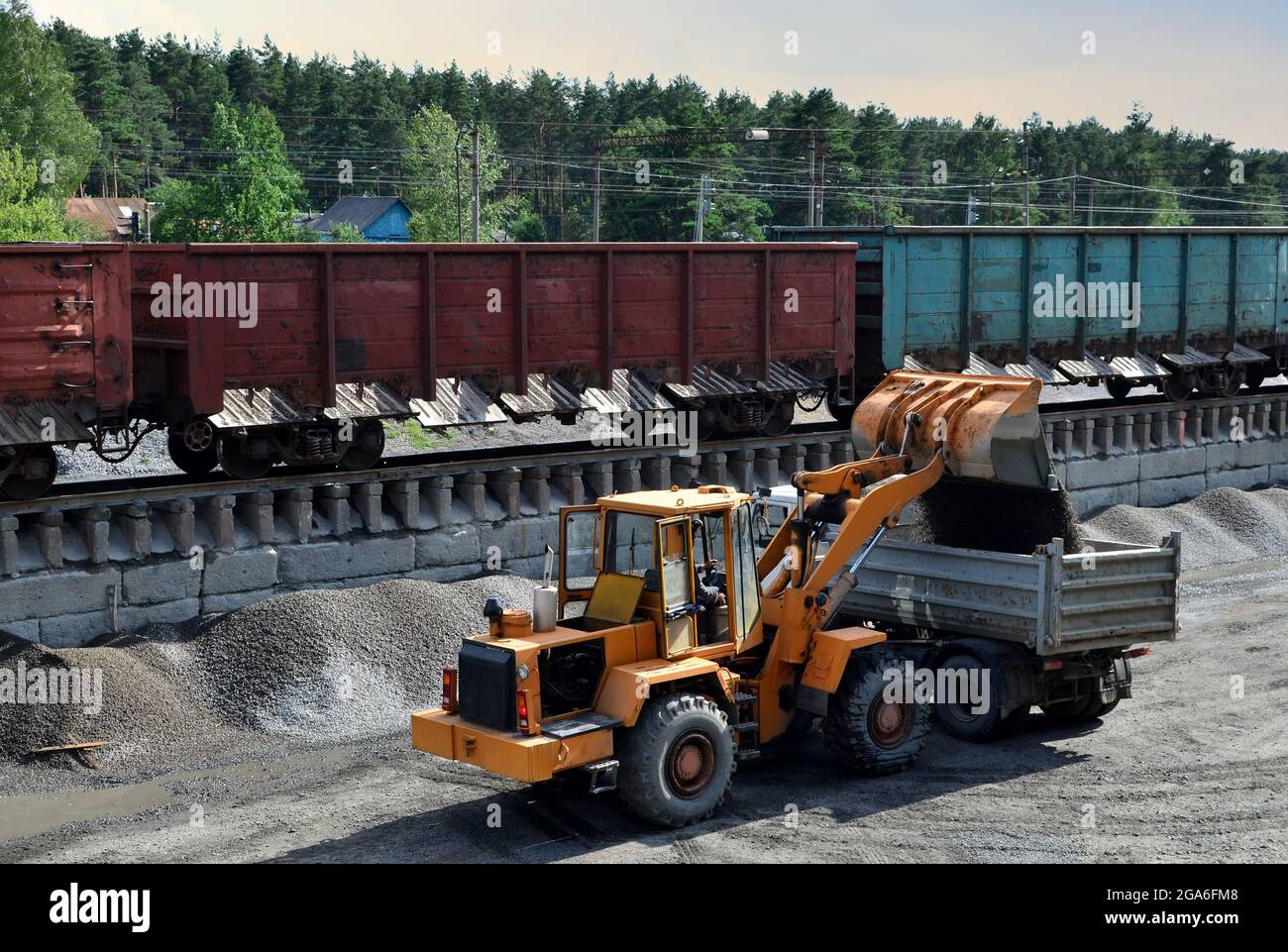 Wheel loader load gravel into a dump truck at a cargo railway station ...
