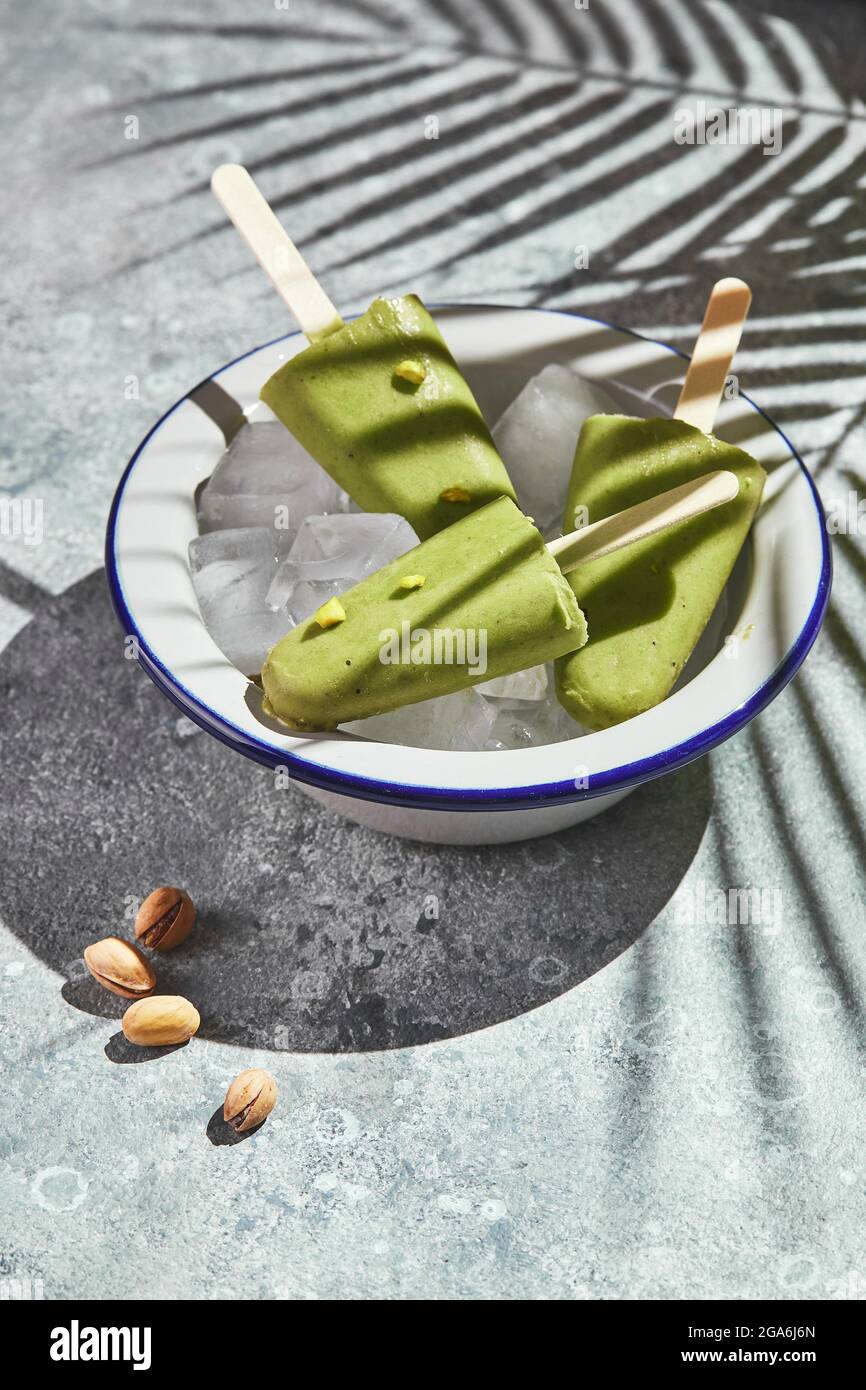 Frozen homemade pistachio popsicle in bowl of ice on gray background ...