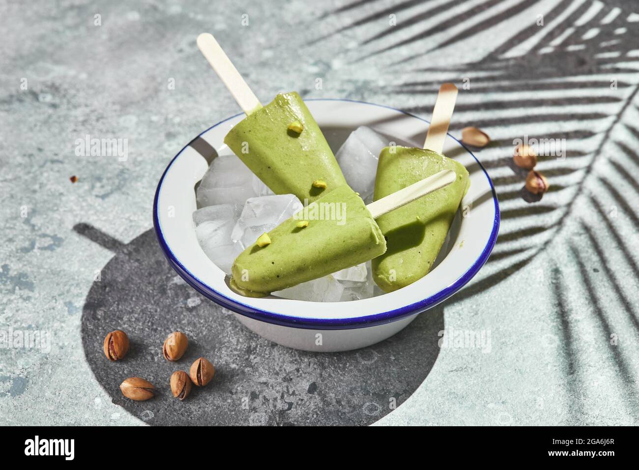 Frozen homemade pistachio popsicle in bowl of ice on gray background ...