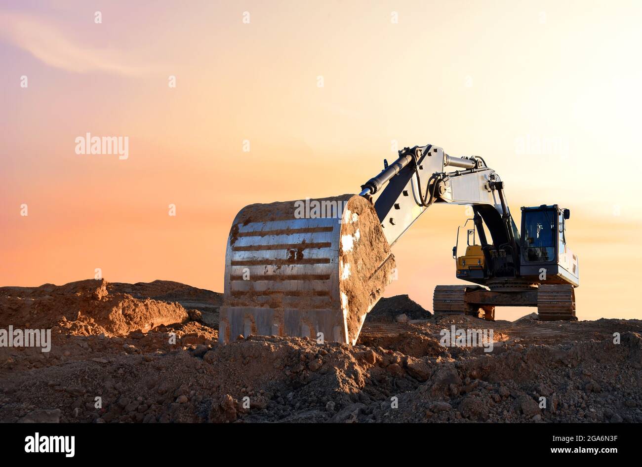Excavator working on earthmoving at open pit mining on amazing sunset ...