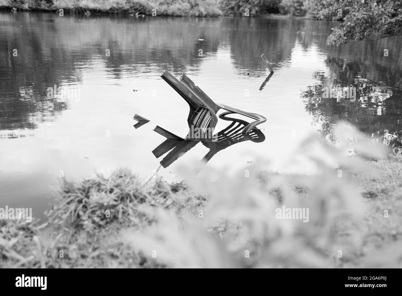 A plastic chair thrown into a lake Stock Photo - Alamy