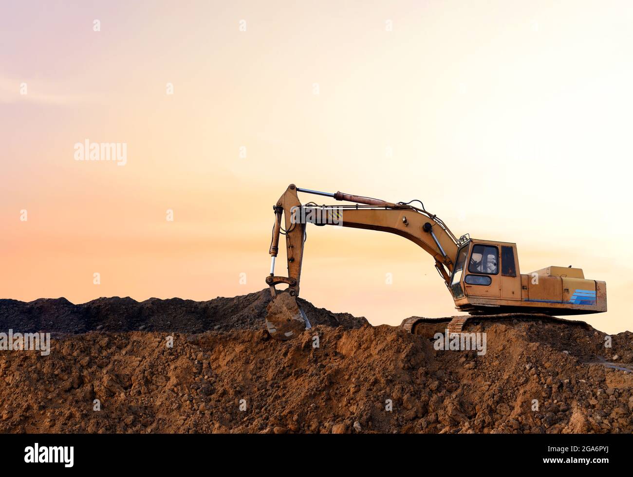 Excavator during earthmoving work at open-pit mining on sunset ...