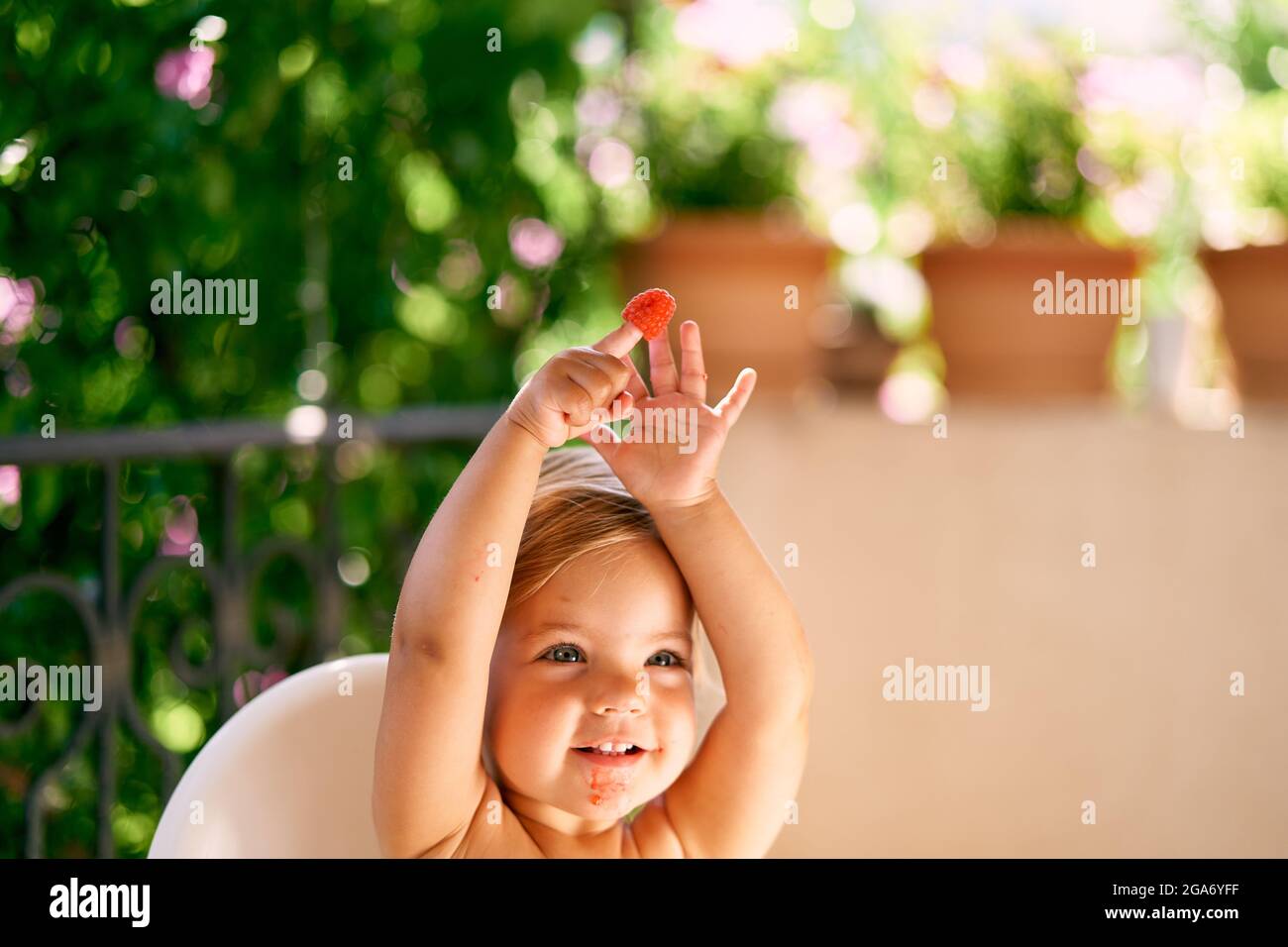 Smiling child with spots on his chin, raised raspberries on a finger ...