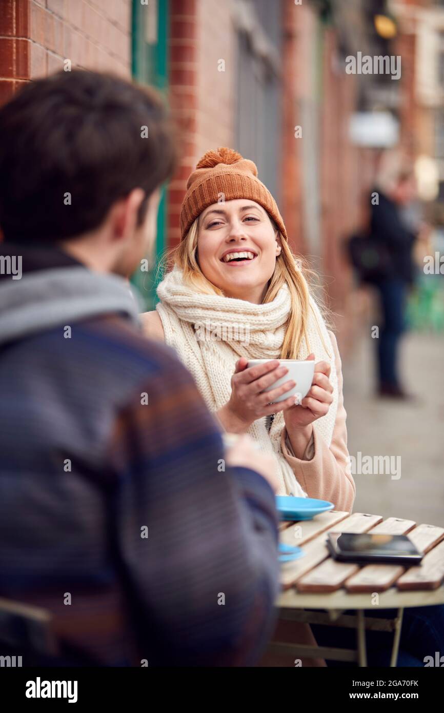 Couple On Date Sitting Outside Coffee Shop On Busy City High Street ...