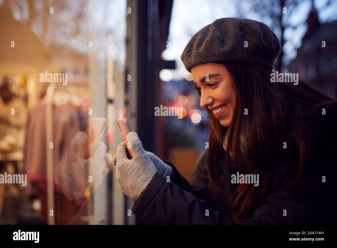 Evening View Of Woman Window Shopping Taking Picture Of Display In ...