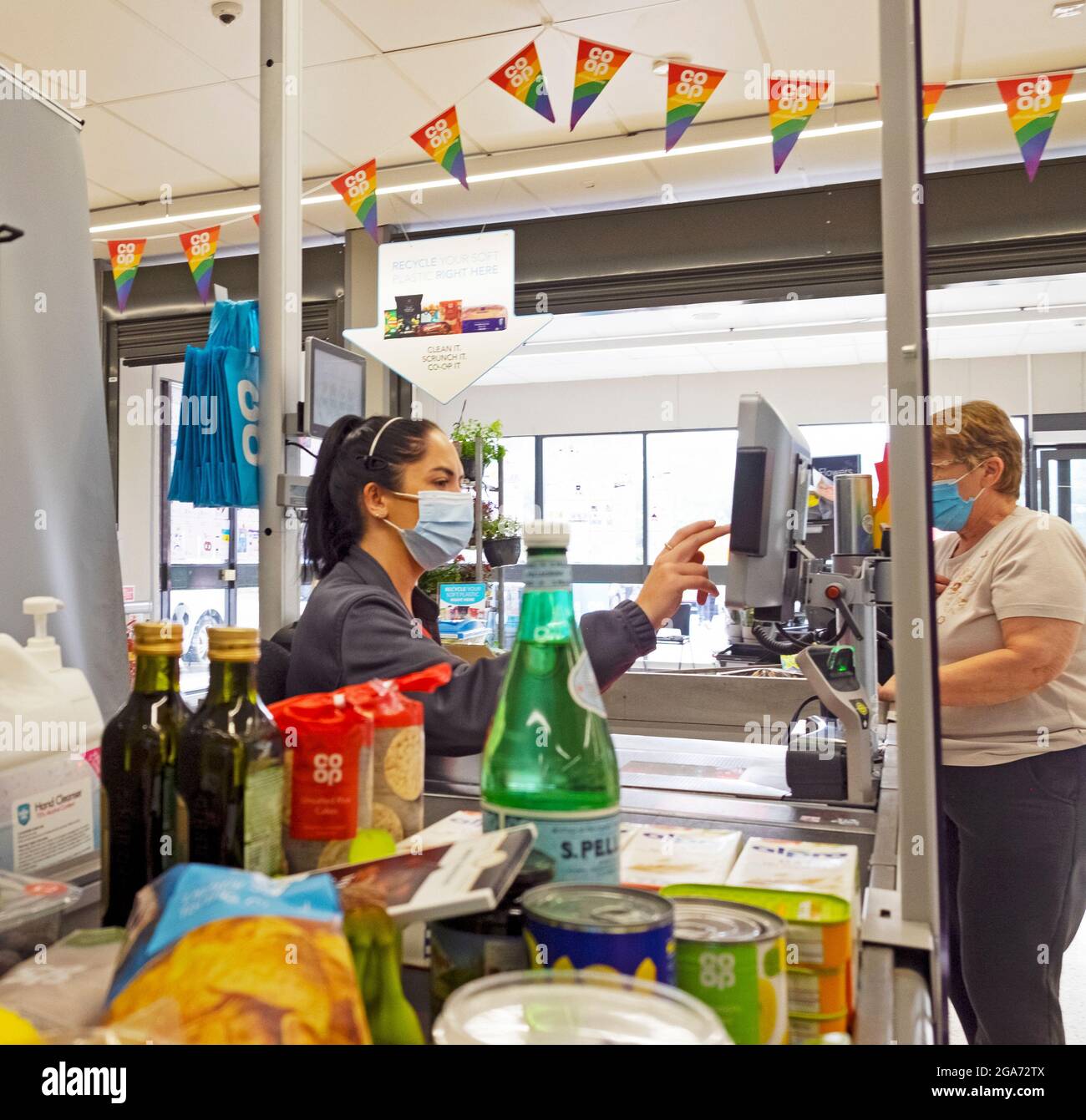 Young woman worker wearing covid facemask in Co Op supermarket working ...