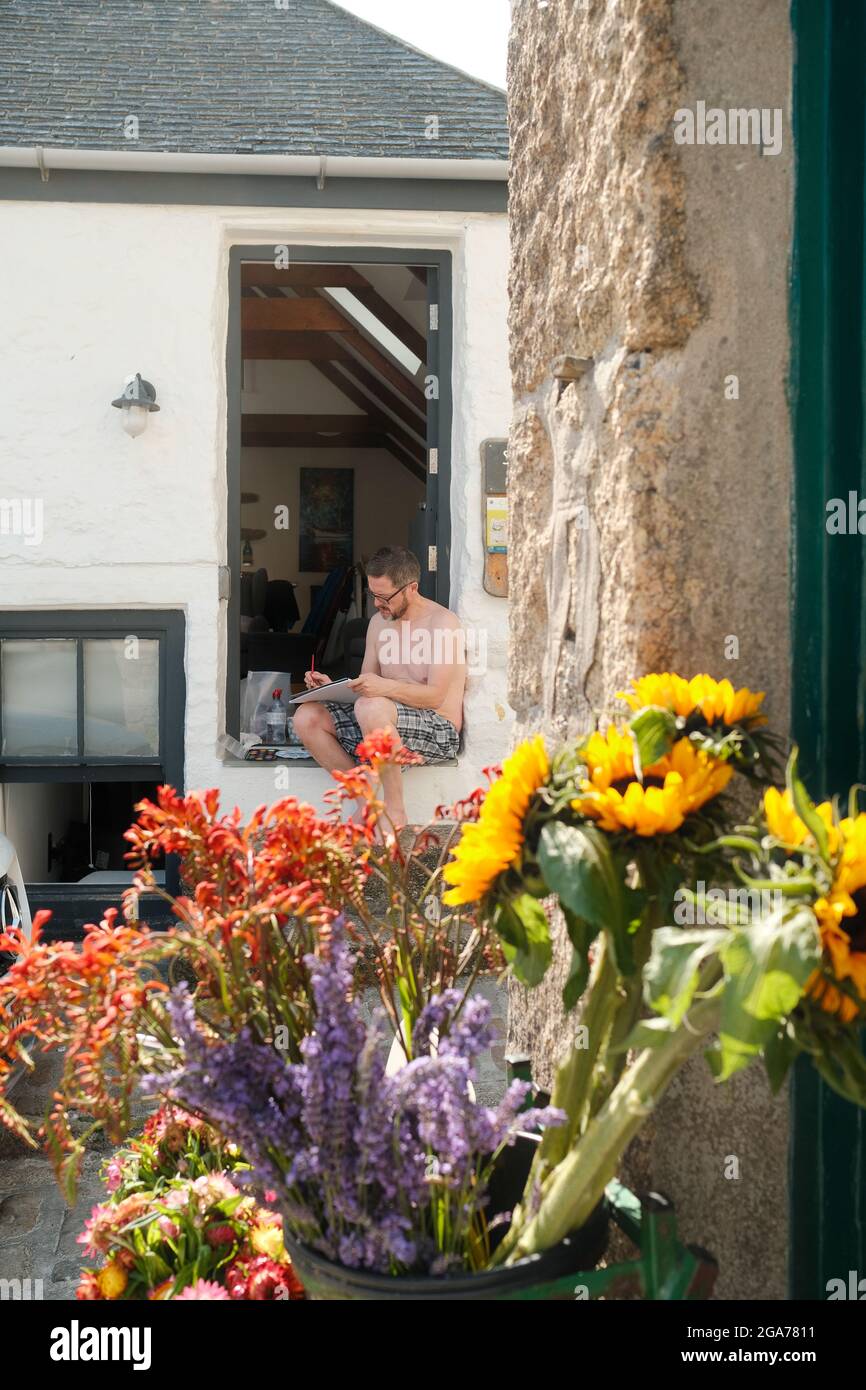 An artist sat on his doorstep drawing in St Ives Cornwall Stock Photo ...