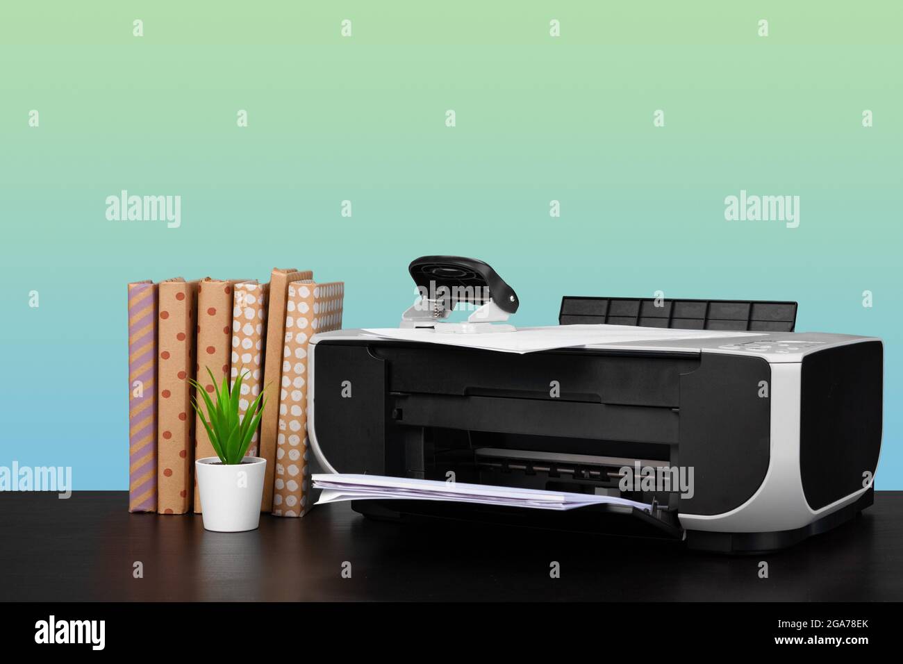 Home laser printer on desk against green background Stock Photo - Alamy