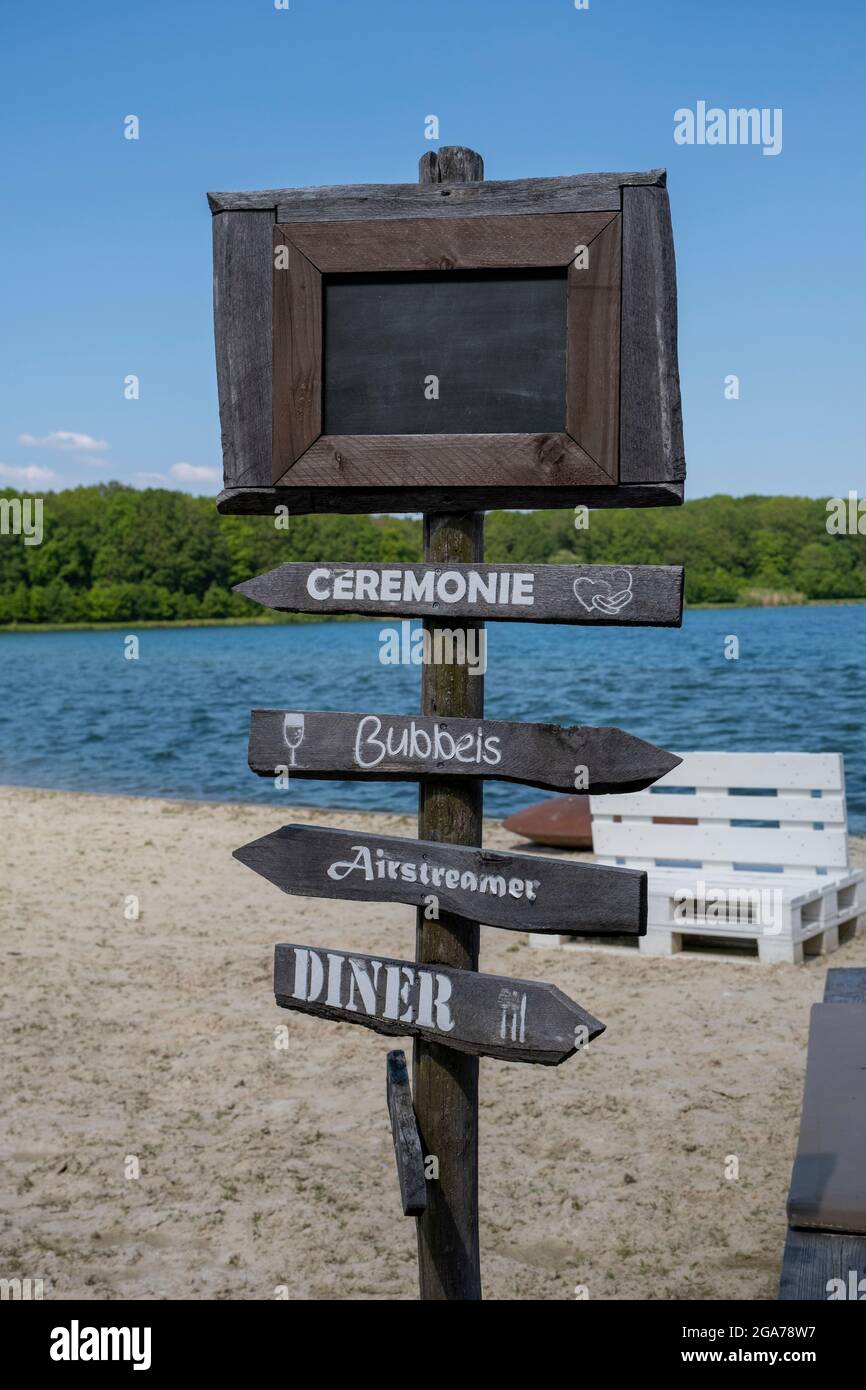 Empty black board on white sand beach with warm sunlight in the ...