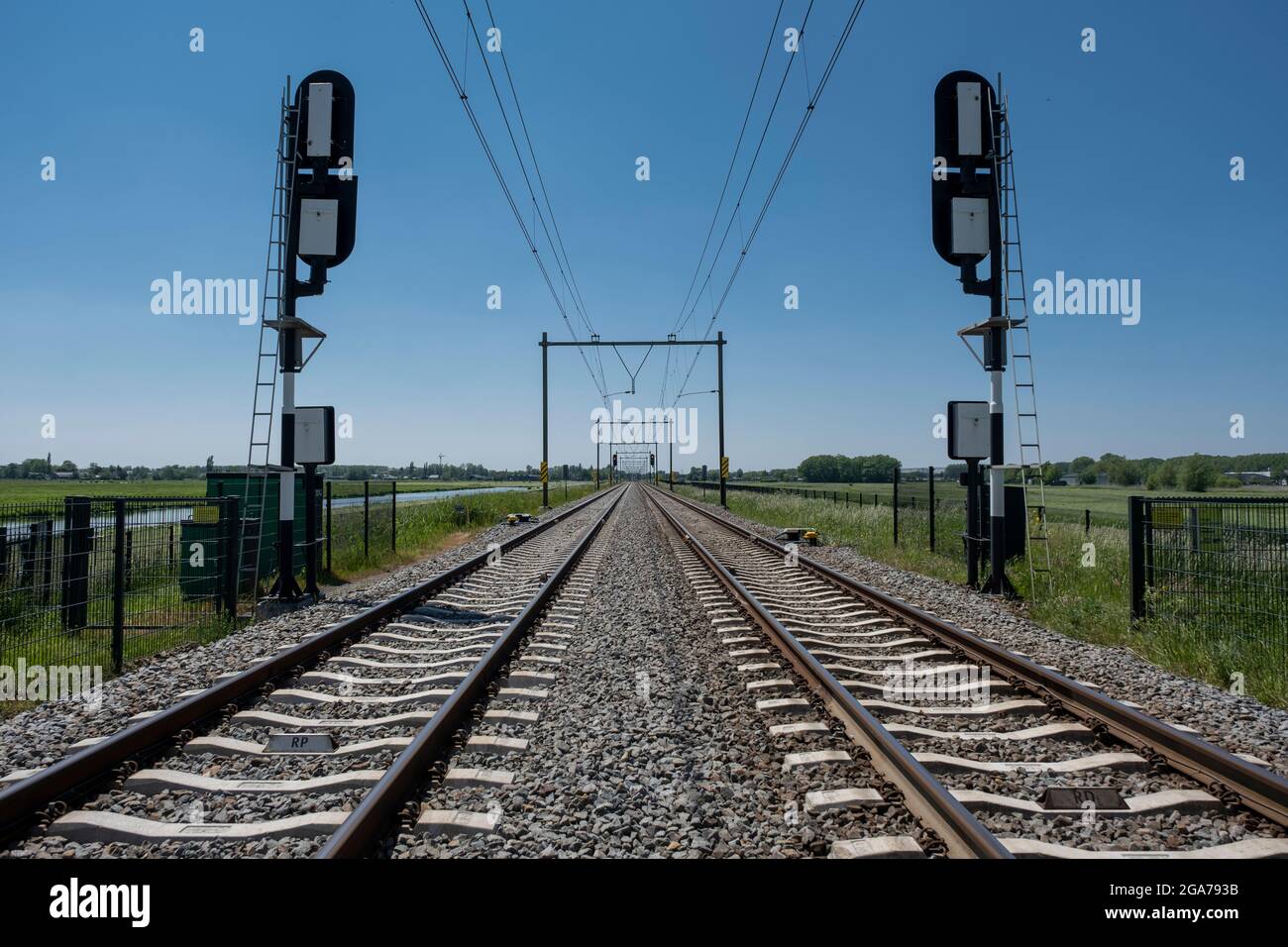 Two railway tracks with electric power cables and on the left side a ...
