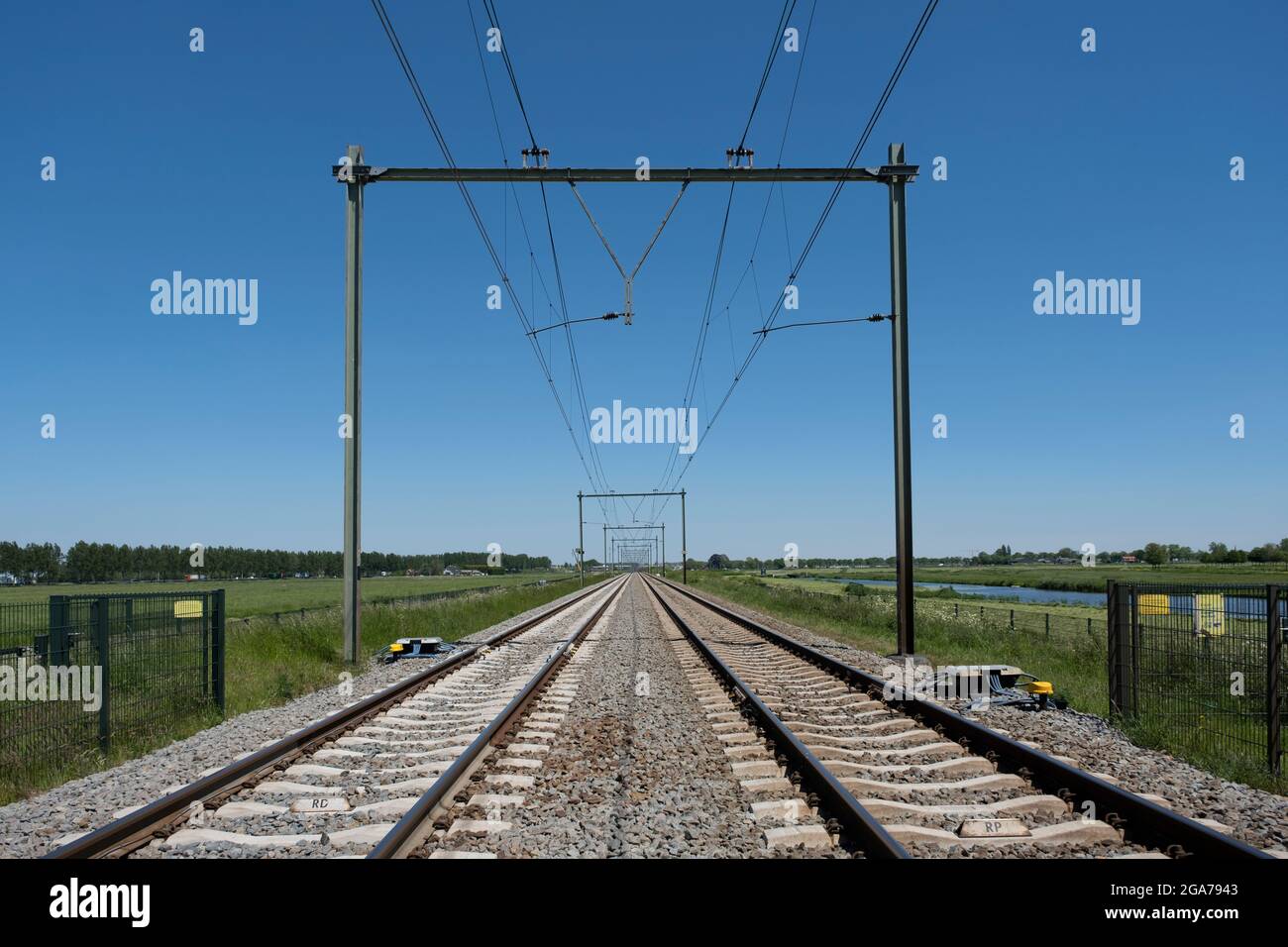 Two railway tracks with electric power cables and on the left side a ...