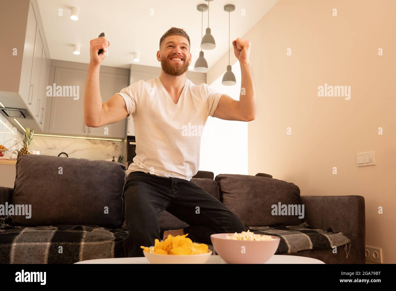 Celebrating man sit on sofa and watch TV or movie Stock Photo - Alamy