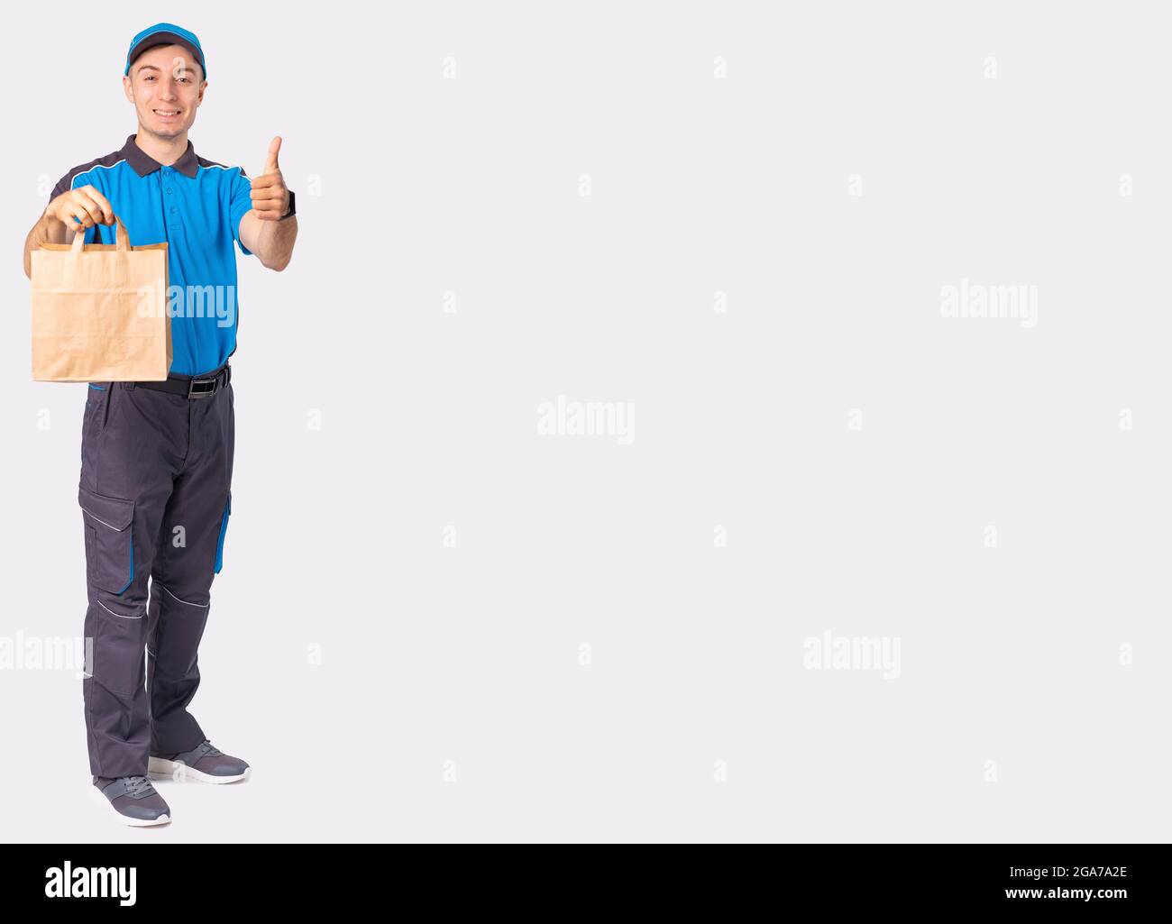 The full-length photo of a man courier poses with the cardboard bag ...