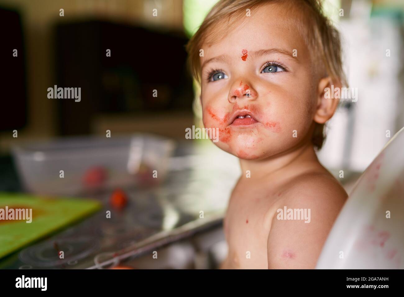 Kid sits at a table with a strawberry-stained face. Portrait Stock ...