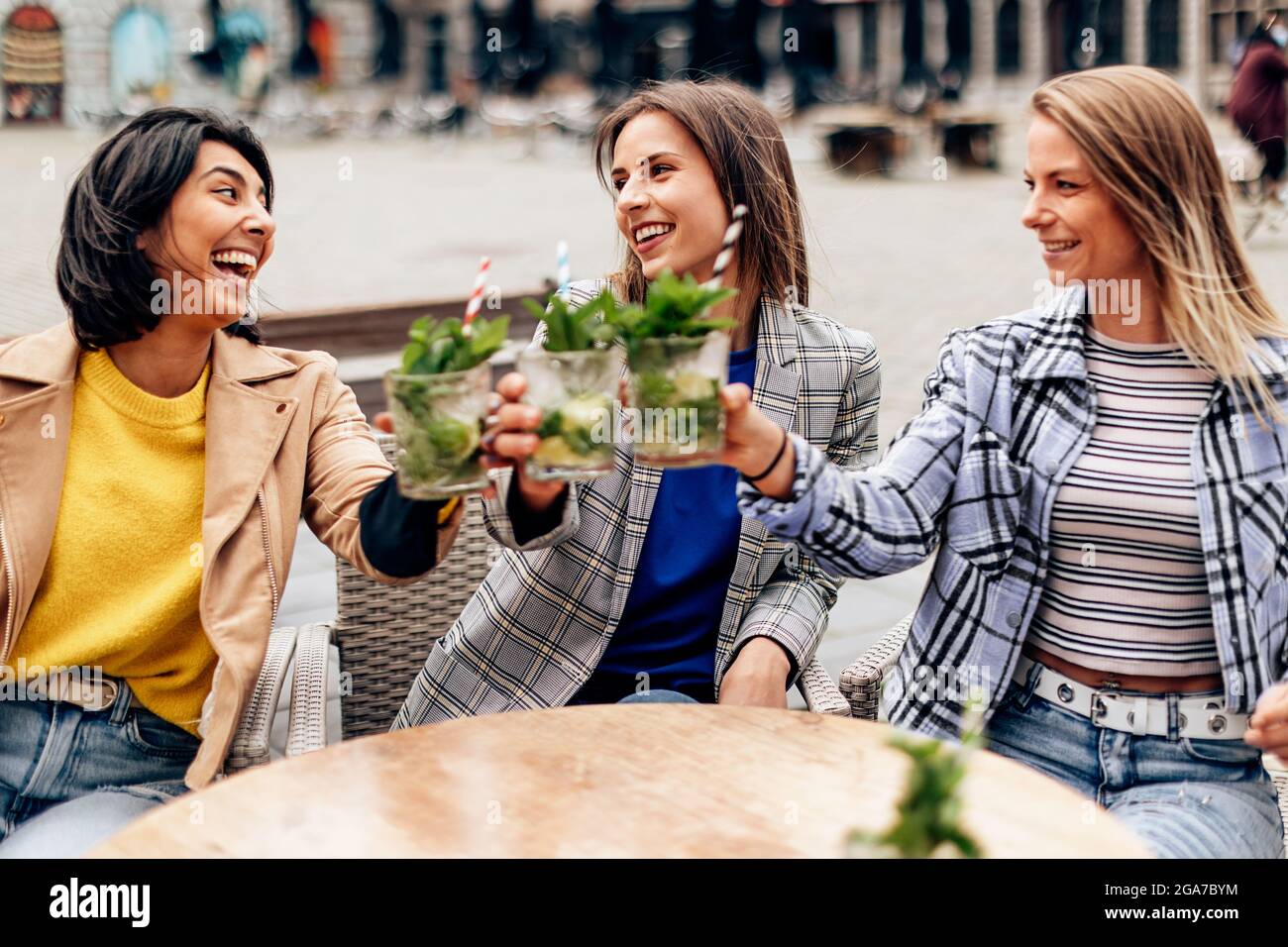 happy three friends young women sitting at the terrace cafe toasting ...