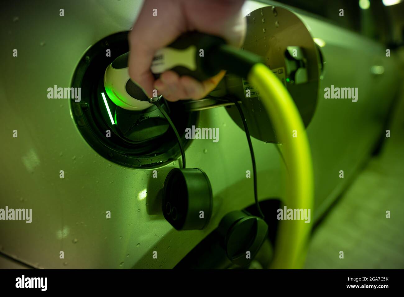 Example for recharging an electric car. A mans hand on the plugged in ...