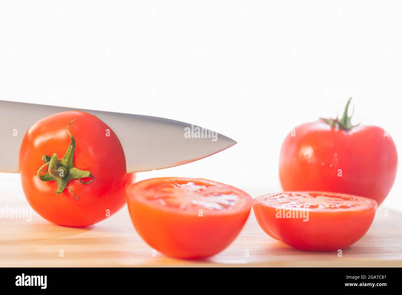 A knife cutting a tomato, a tomato cut in half and a whole tomato Stock ...