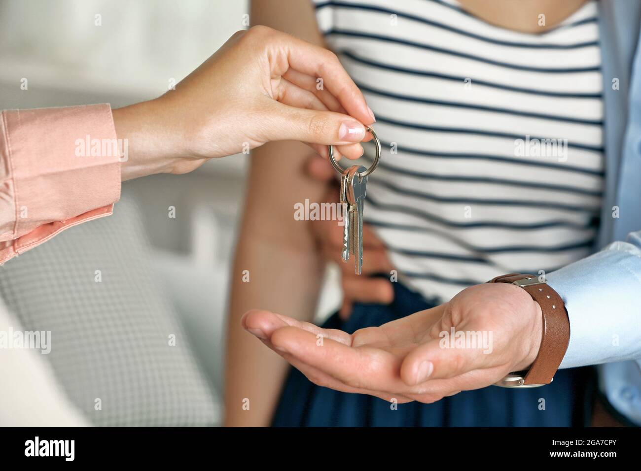 Real estate agent giving keys to young couple Stock Photo - Alamy