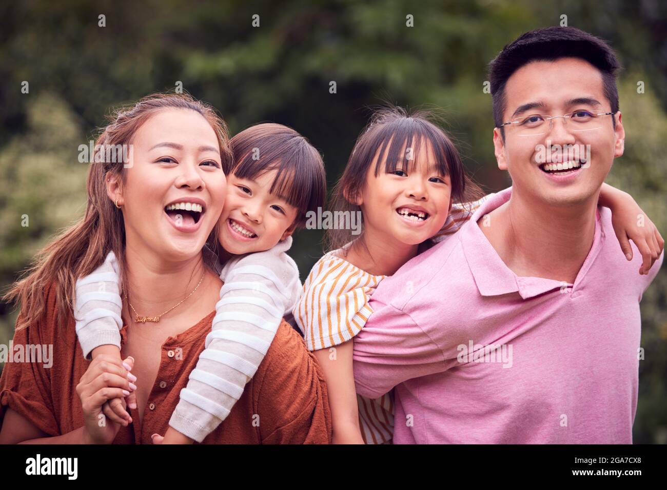 Portrait Of Smiling Asian Family Outdoors With Parents Giving Children ...