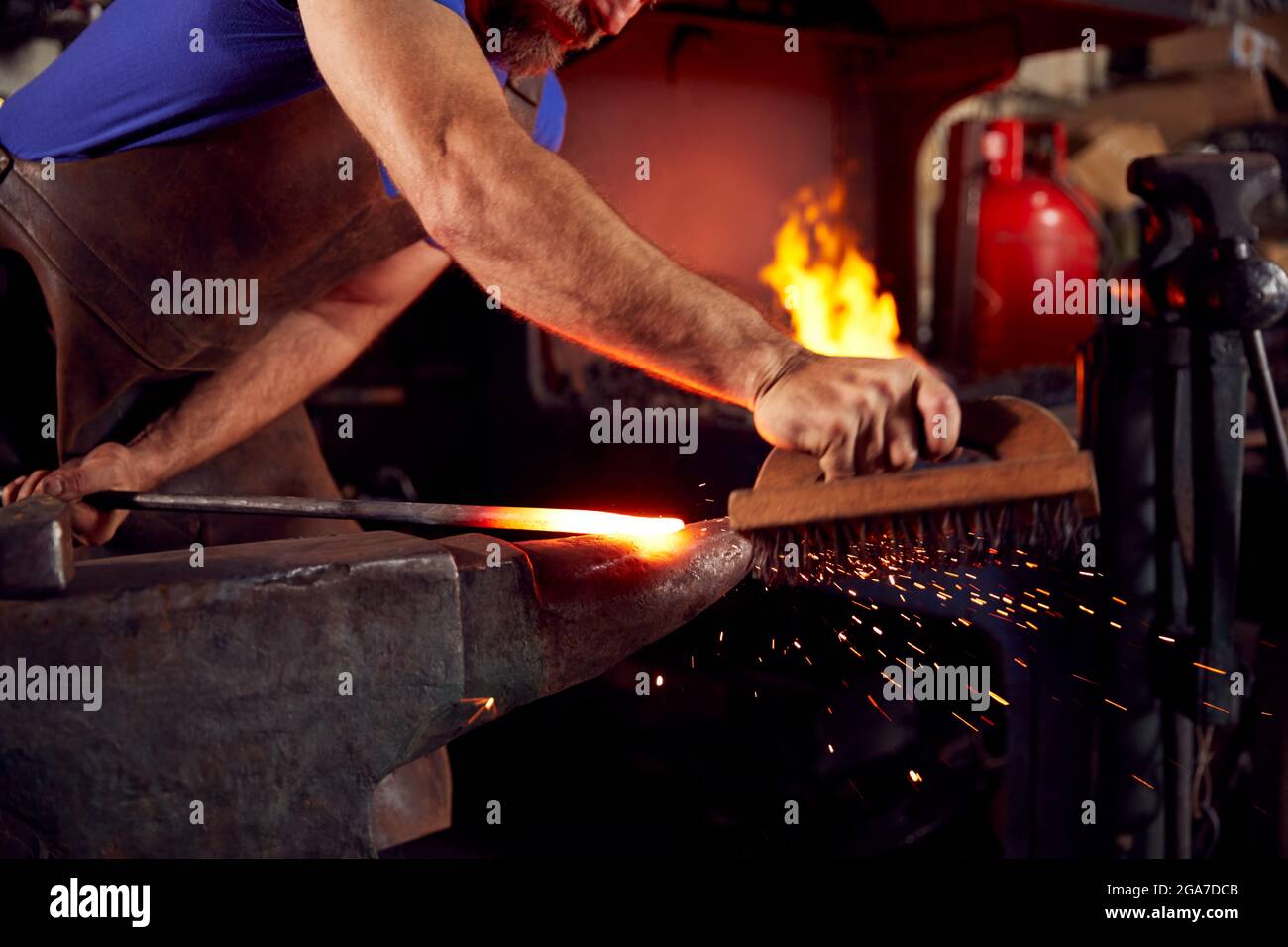 Close Up Of Male Blacksmith Using Wire Brush On Metalwork Resting On ...