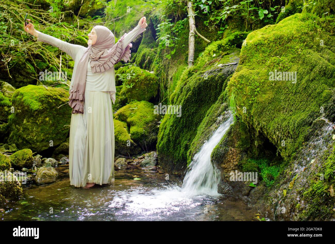 A young Muslim woman with hijab untouched nature, enjoys the natural ...