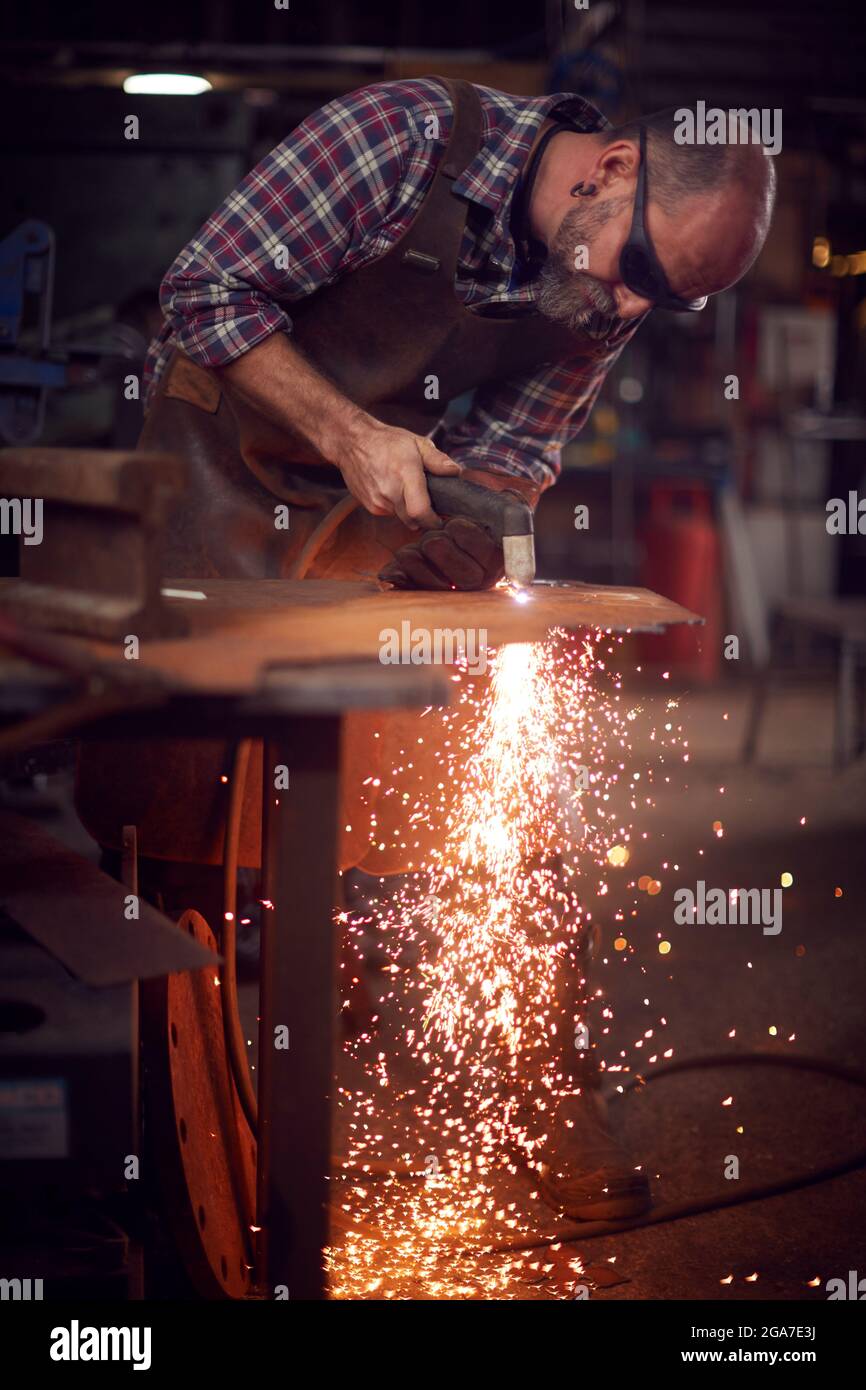 Male Blacksmith Using Plasma Cutter To Cut Shape From Sheet Metal In ...