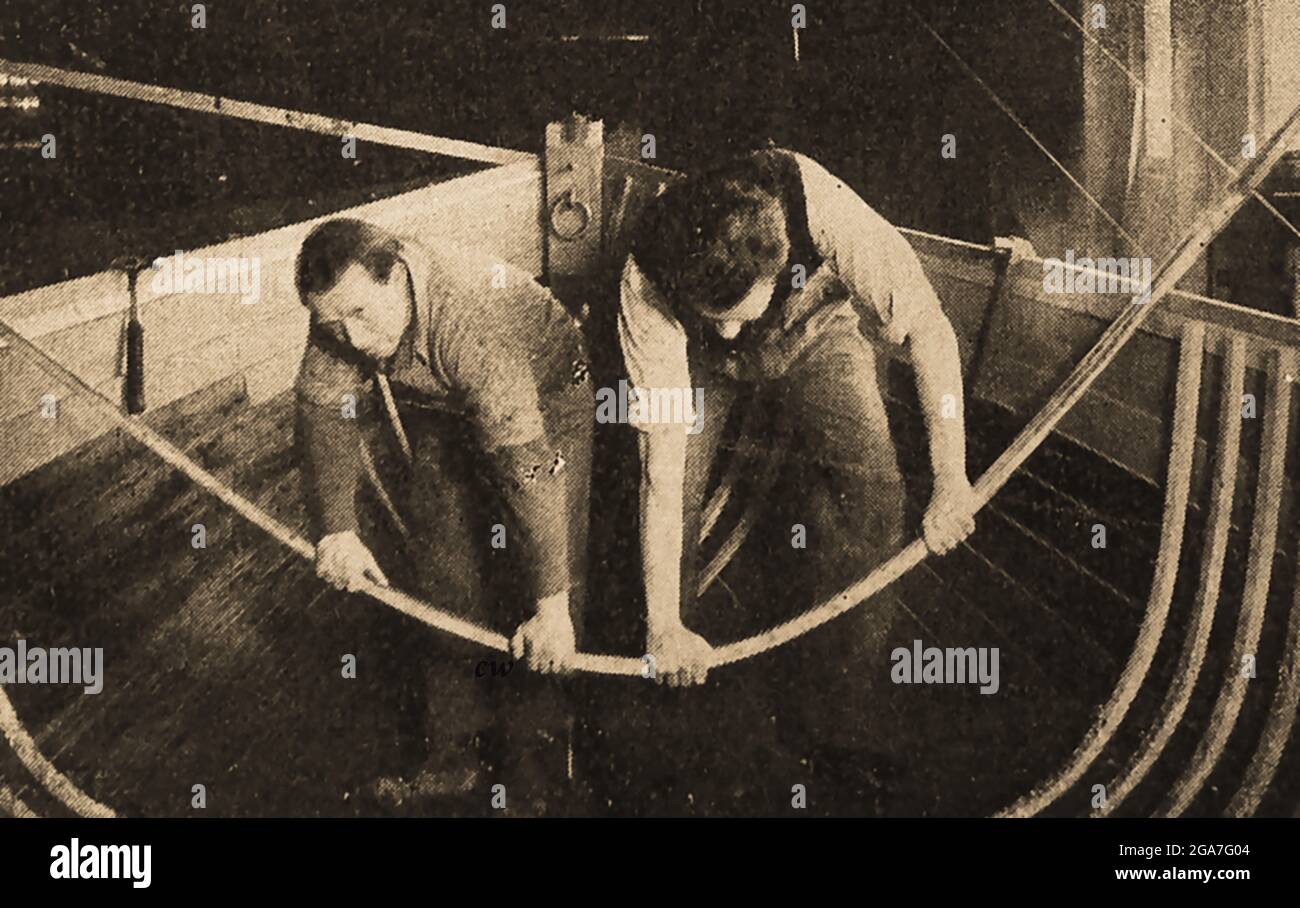 An old printed photograph of men placing a steamed plank into position ...
